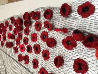 Attaching crafted poppies to display netting. | charlbury.info